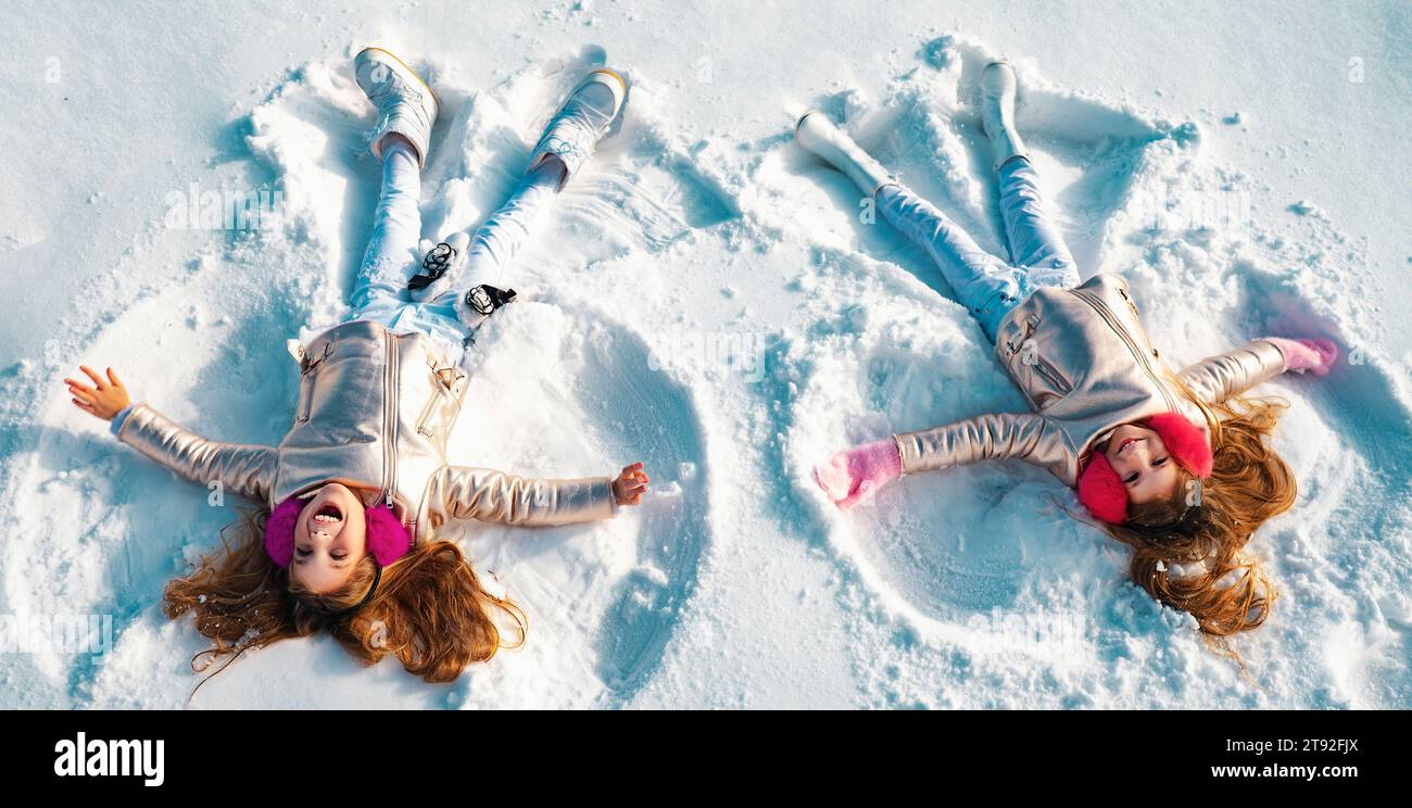 Winter angels. Happy kids girls on make snow angel wings. Two children ...