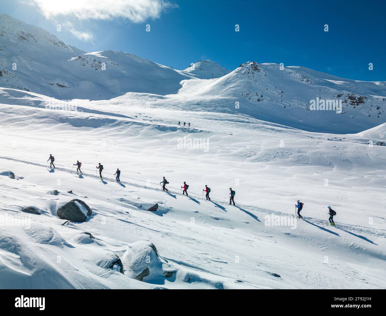 Aerial view of a trekking group ascending french alps in line leaving ...