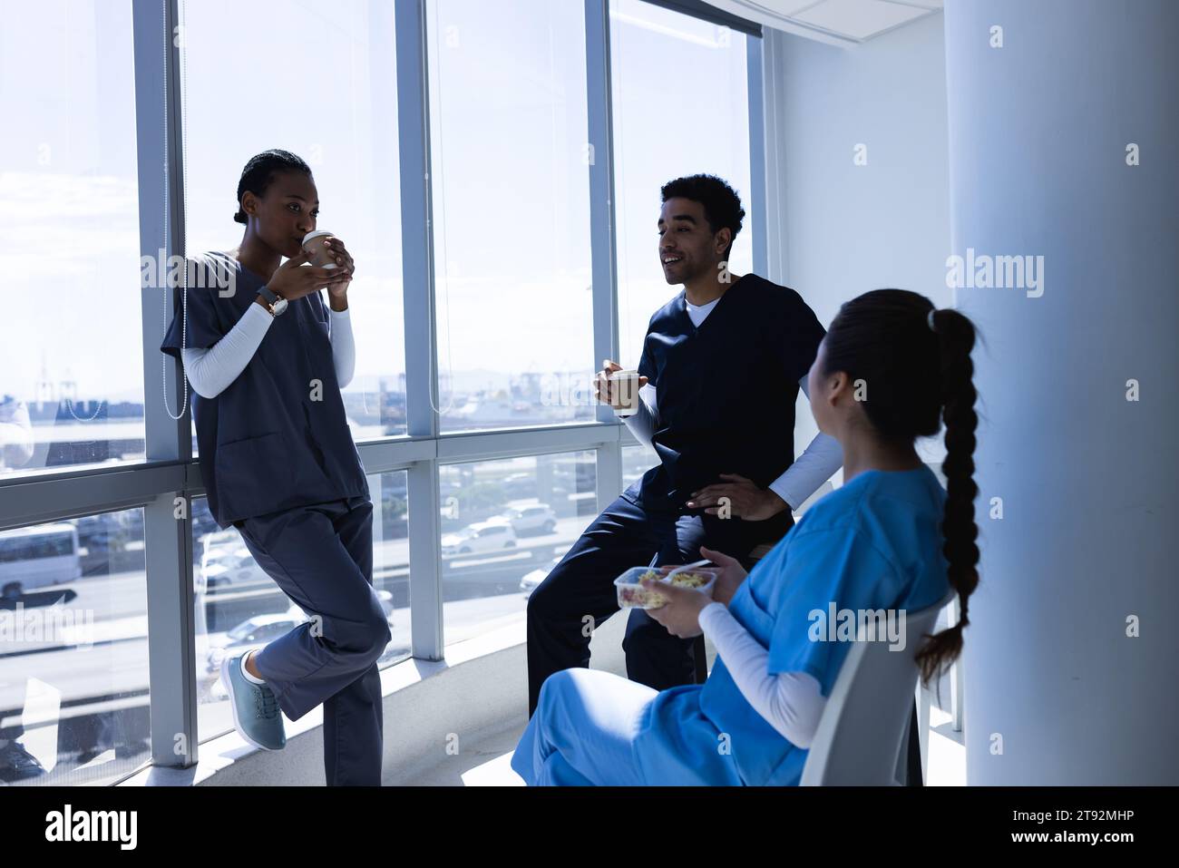 Diverse male and female doctors talking, drinking coffee and eating ...