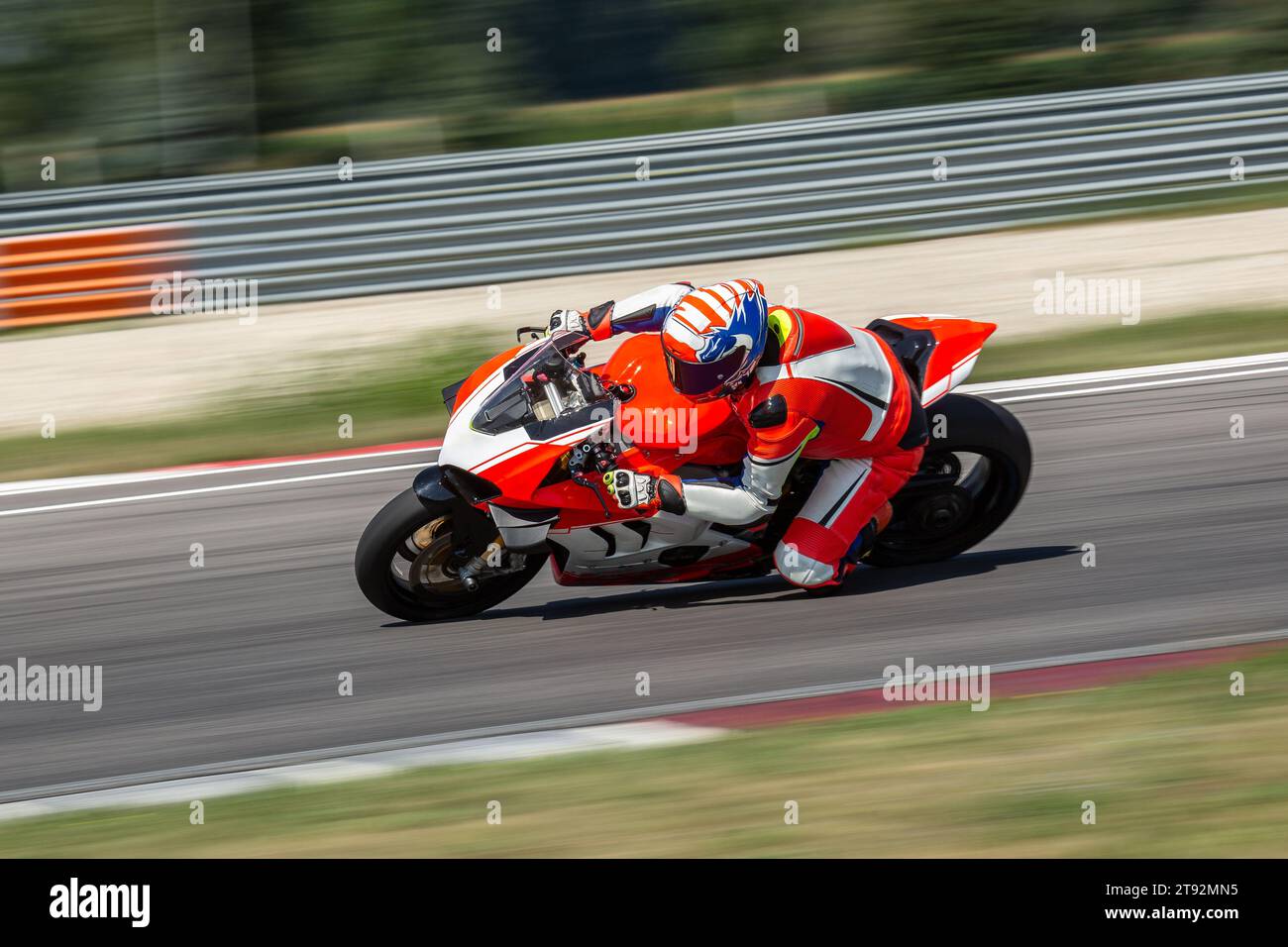 red sport motorcycle riding through corner at high speed, rider is ...