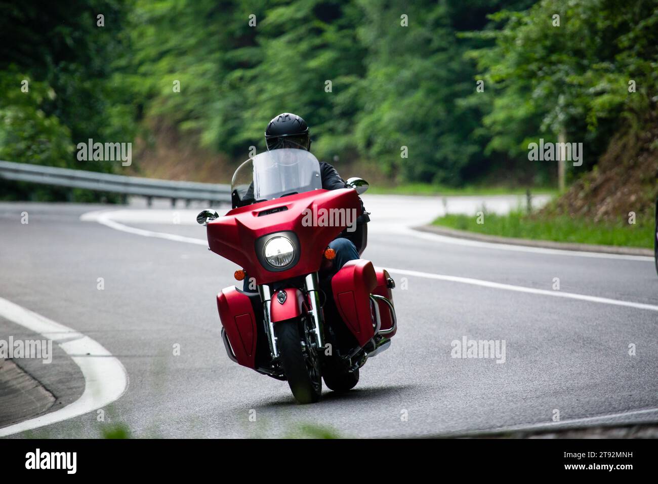Motorcycle rider on a red cruiser motorcycle riding down the mountain ...