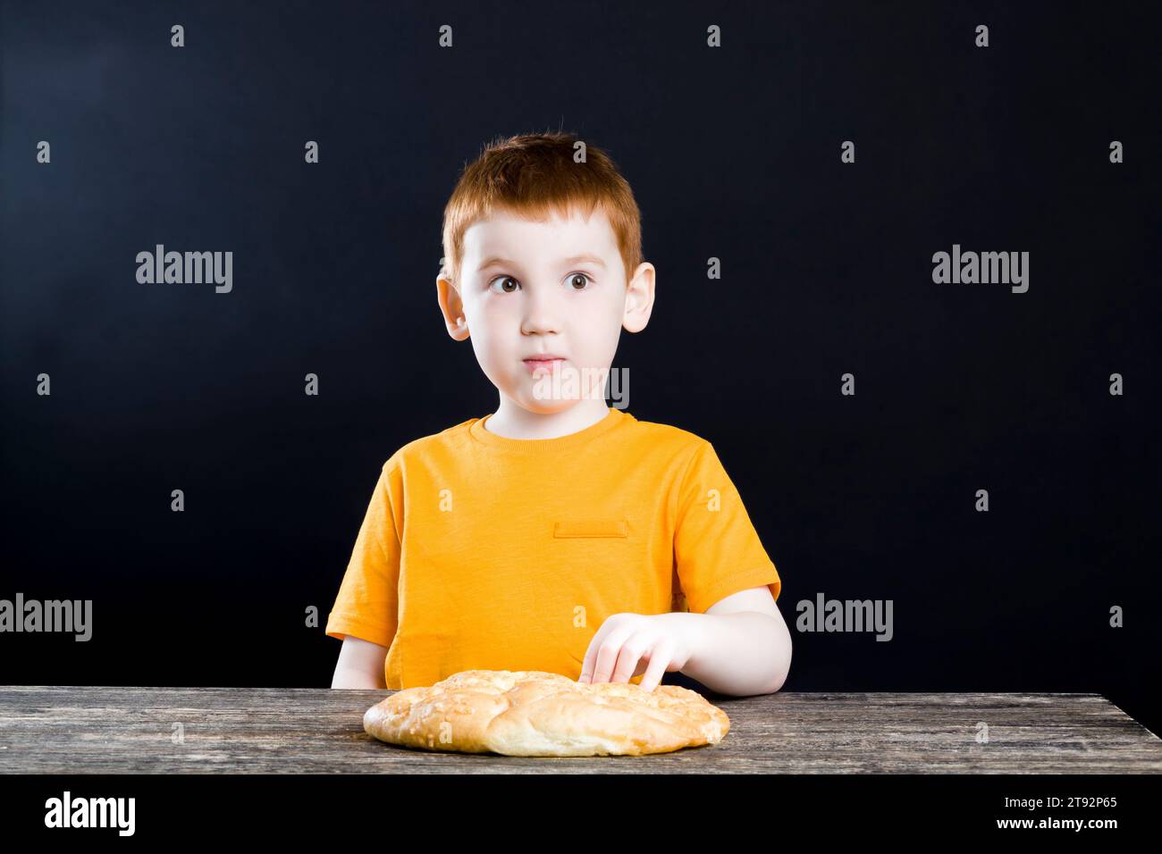 beautiful red-haired boy with a delicious loaf of bread ,boy eats bread ...
