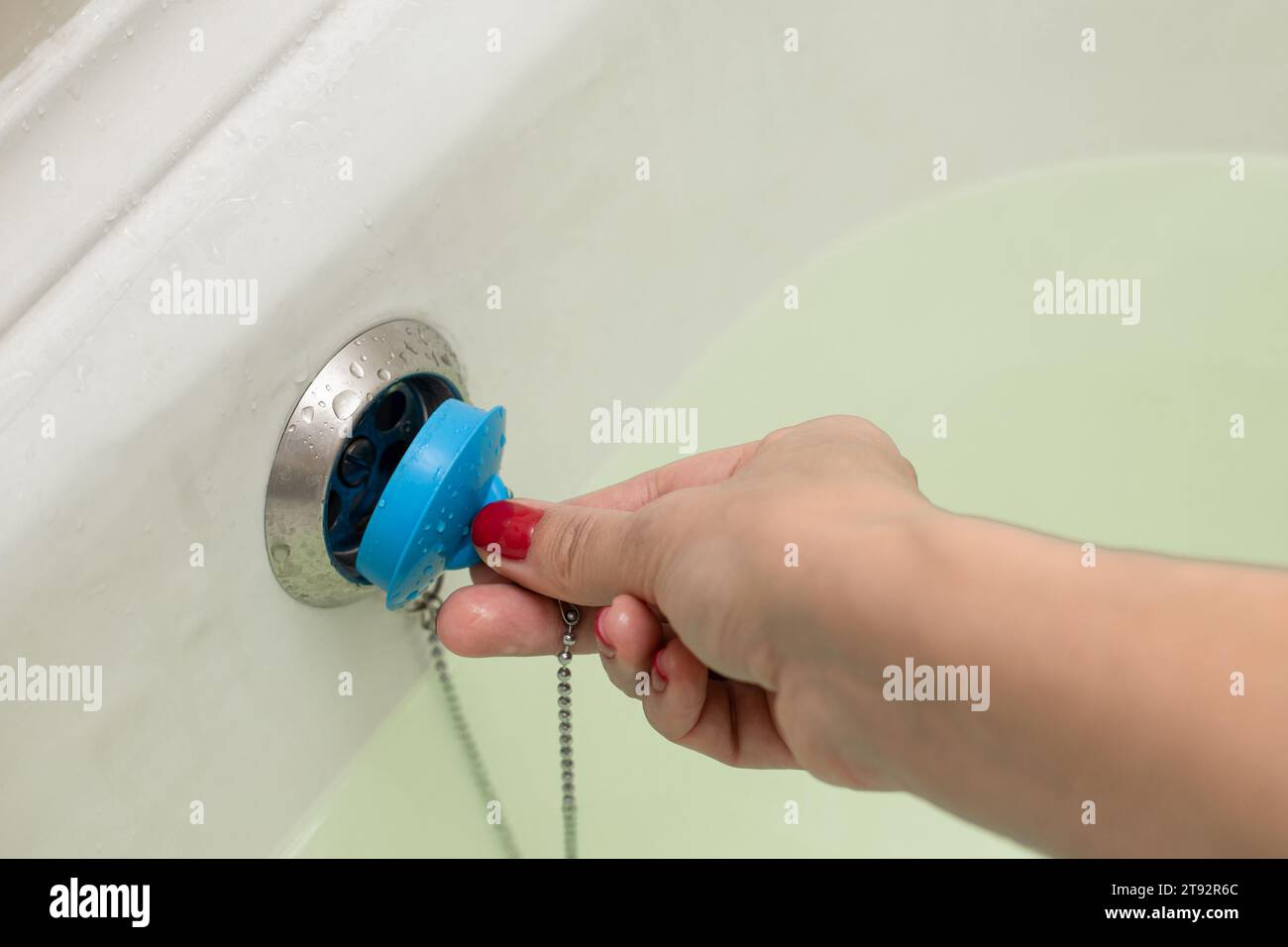 woman's hand closes the drain hole in the bathroom. drain hole in the ...