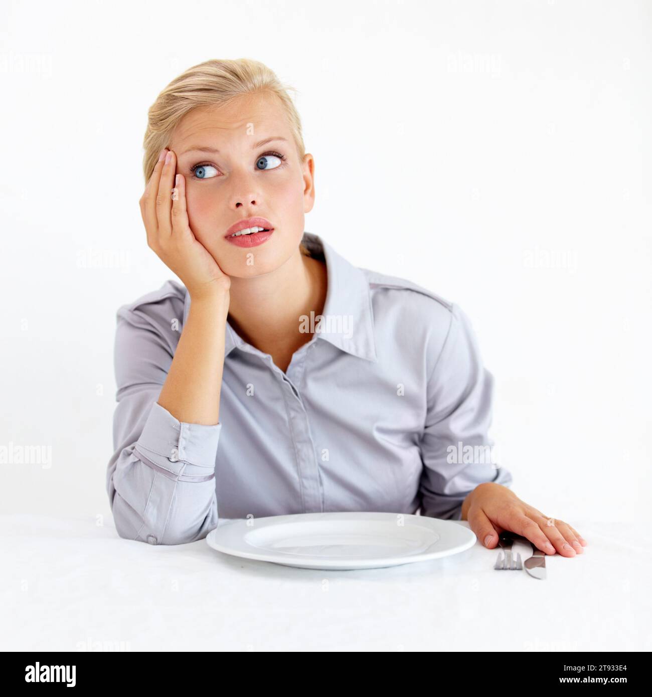 Bored, upset and woman with a plate in a studio with starving ...