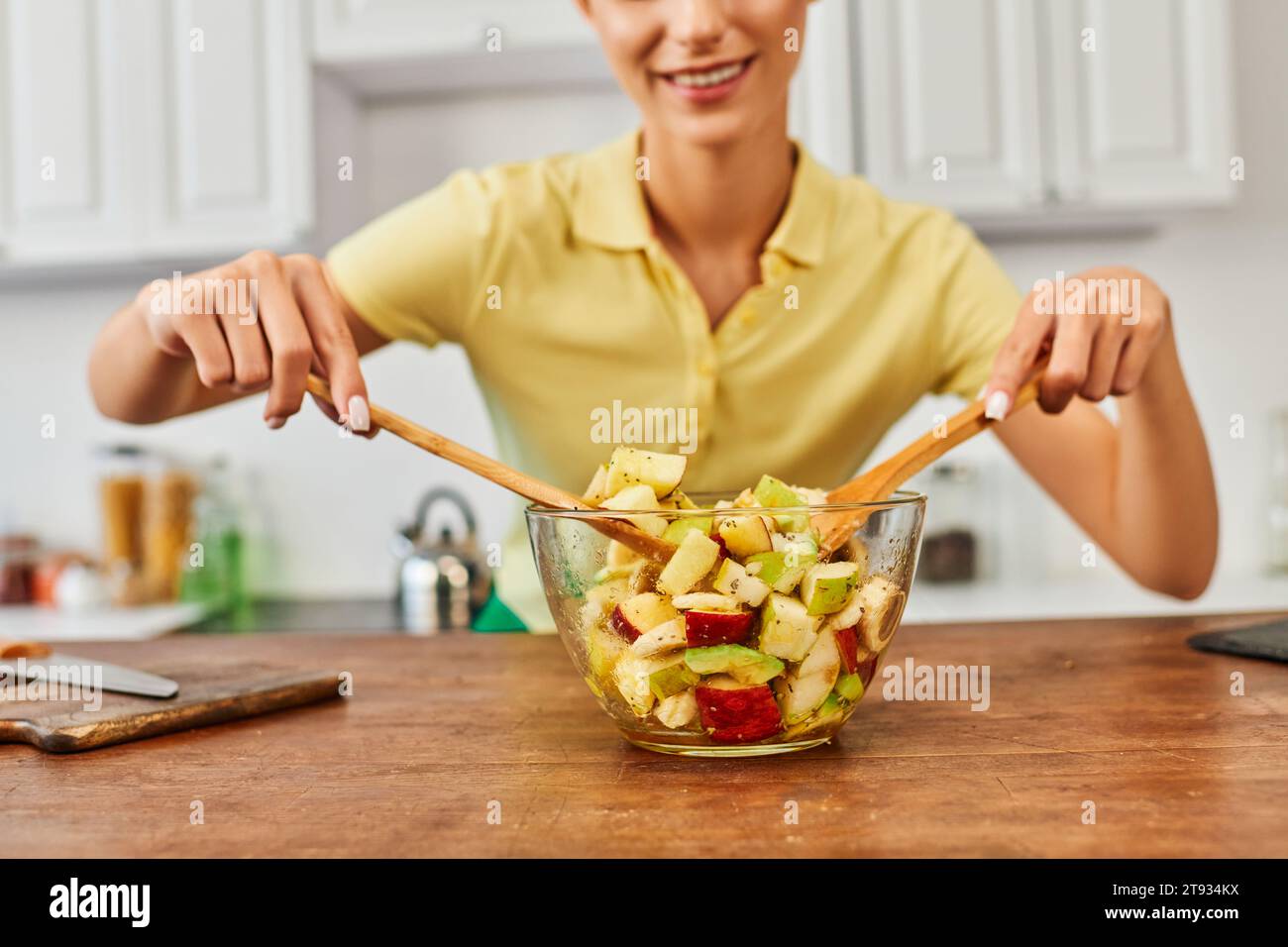 partial view of woman mixing fresh fruit salad with wooden spatulas in ...