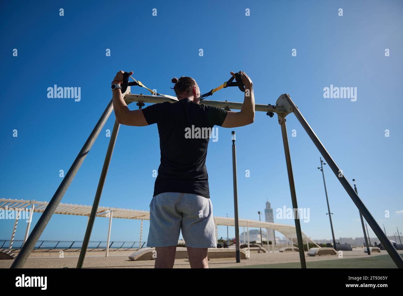 Rear view of a young attractive athletic man doing upper body exercise ...