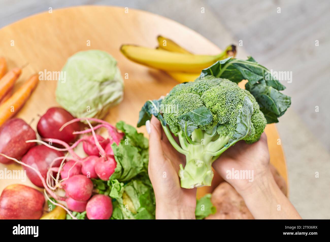 top view of female hands with fresh broccoli over vegetables and fruits ...
