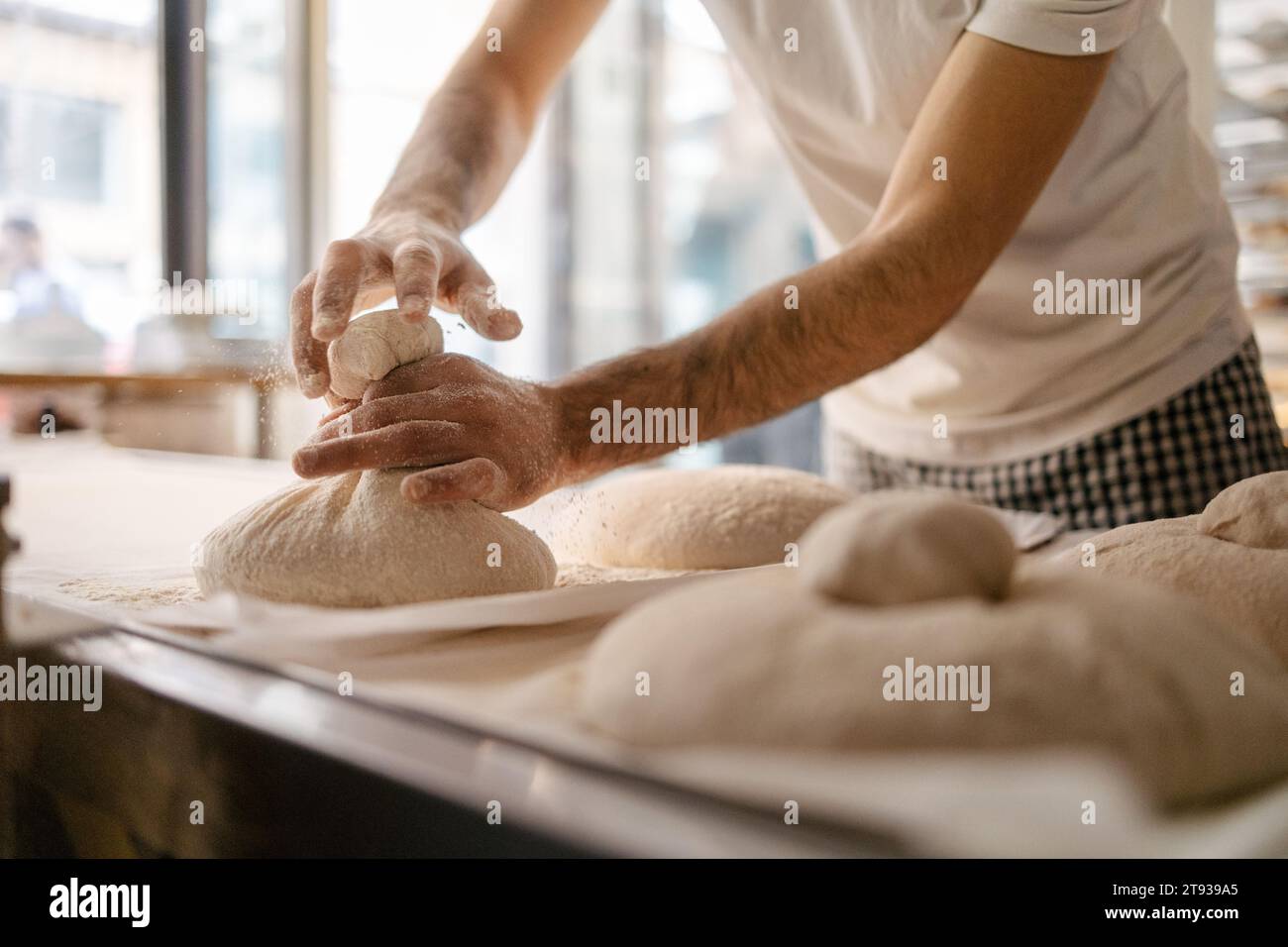 Hands of an unrecognizable male baker in a white t-shirt grabbing bread ...