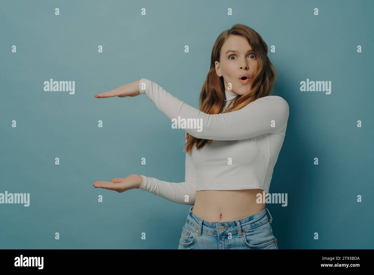 Surprised young woman gesturing with hands, showing size, with an ...