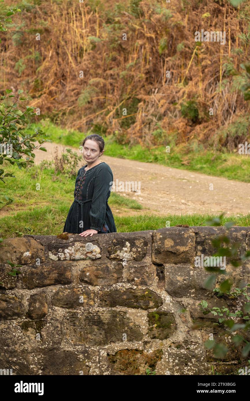 girl stood leaning against wall by a stream contemplating life in the ...