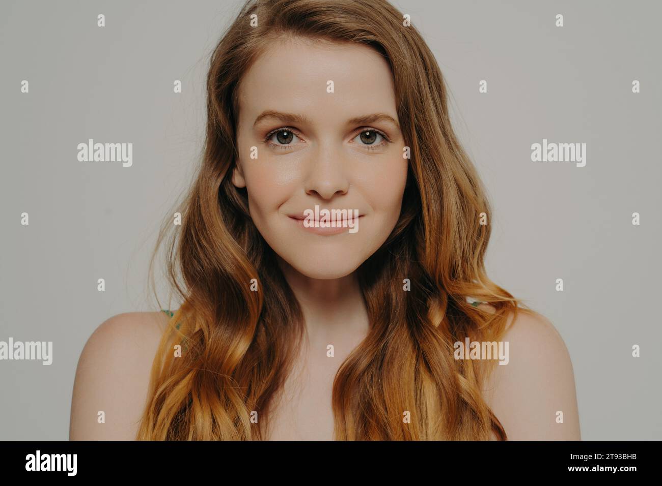 Serene beauty with a subtle smile and wavy hair, wearing a mustard top ...