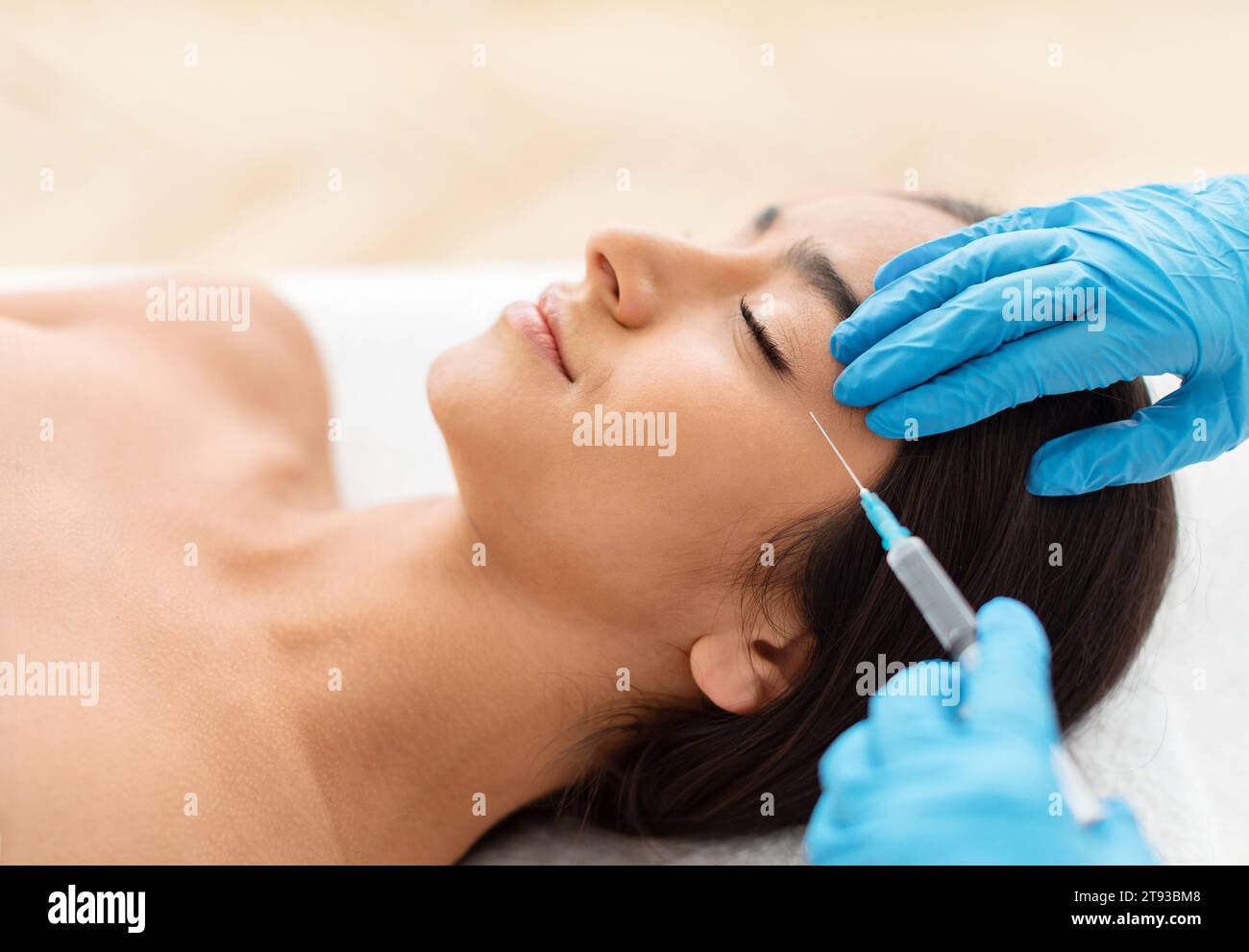 Attractive young indian woman undergoing aesthetic injection in the eye ...