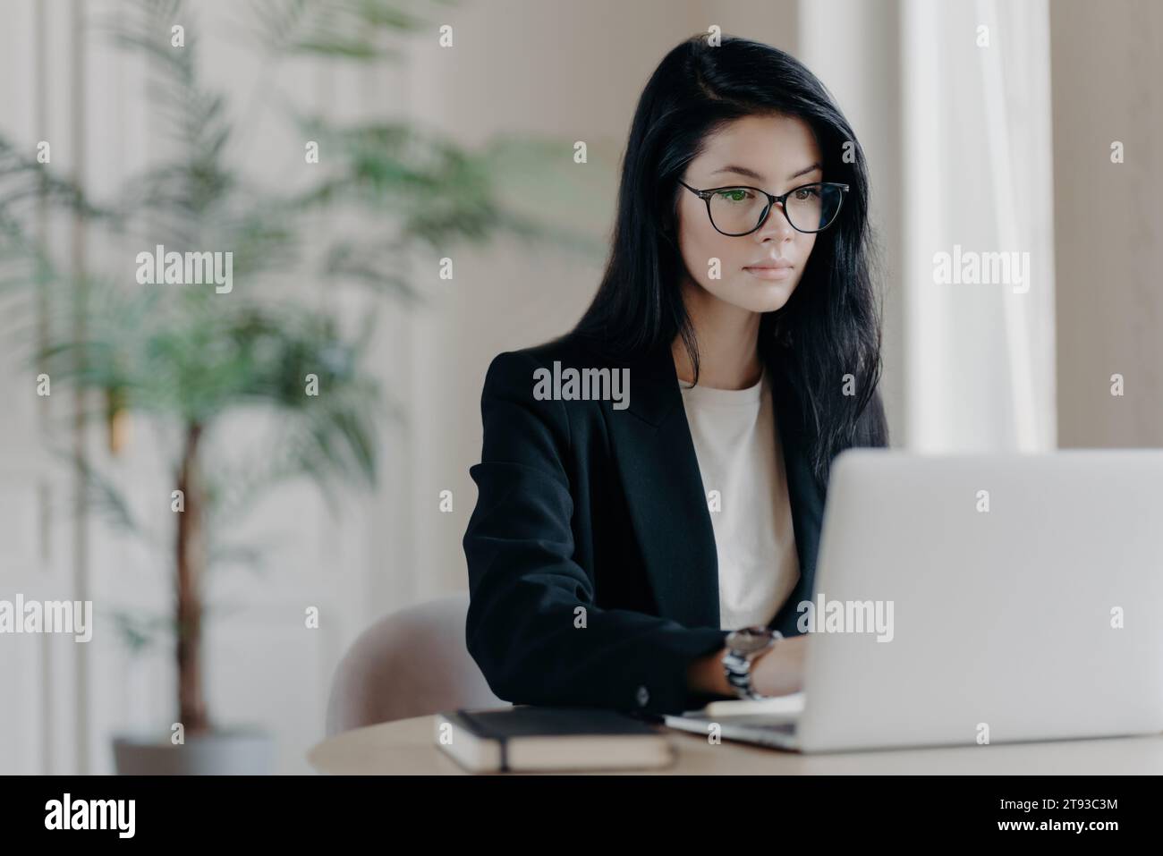 Dedicated professional woman working intently at her laptop in a bright ...