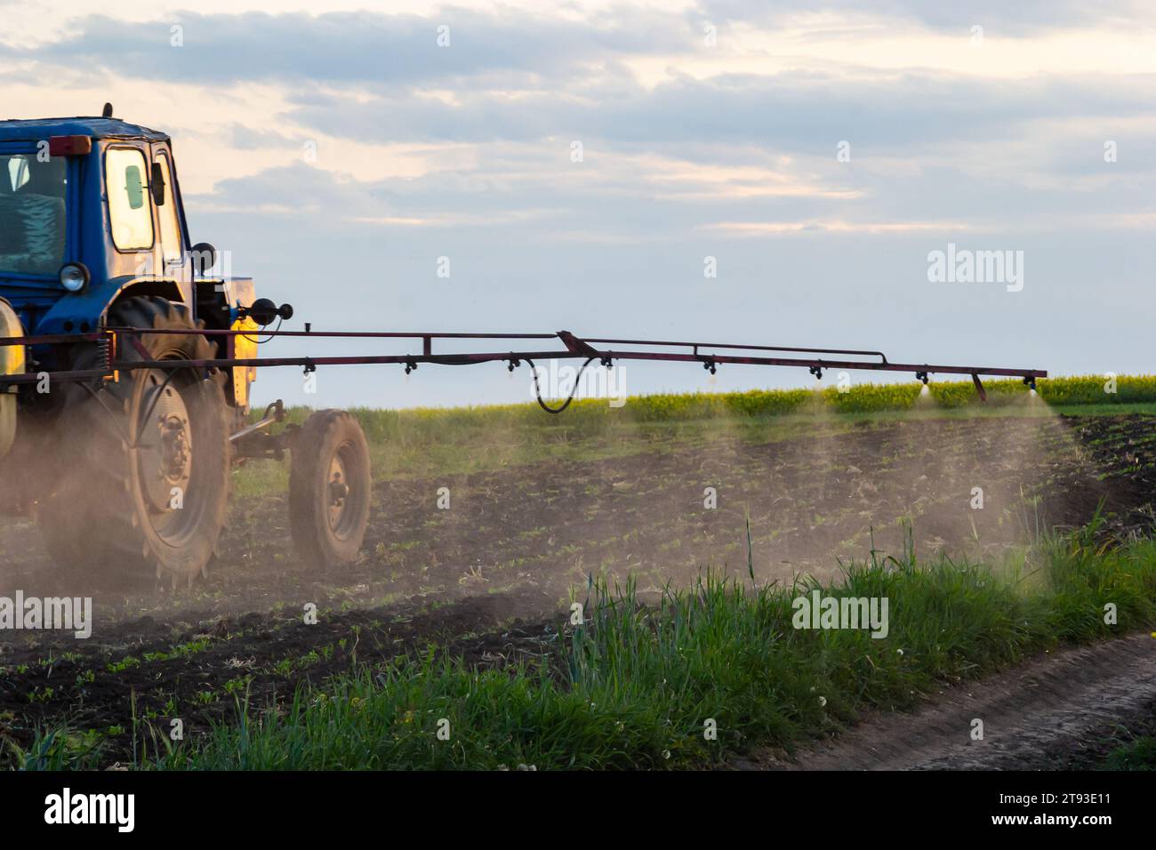 Tractor spraying pesticides on vegetable field with sprayer at spring ...