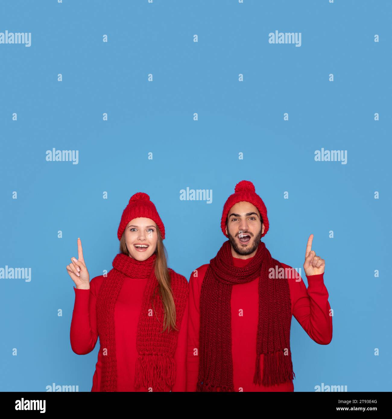 Young Excited Couple Wearing Knitted Hats And Scarfs Pointing Index ...