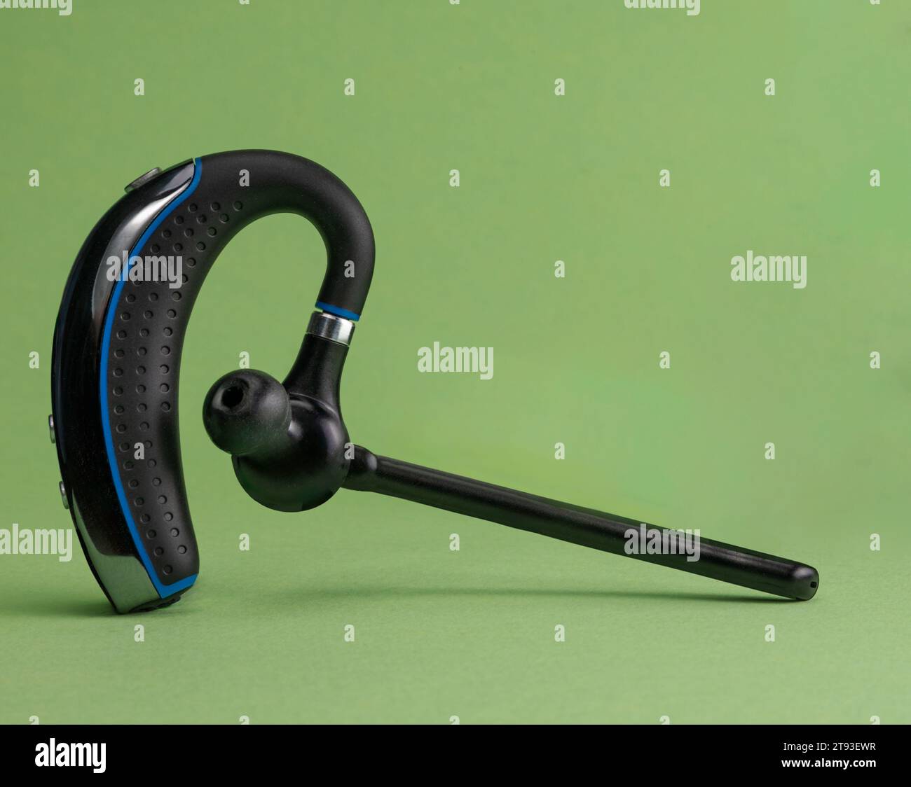 A close up of a Bluetooth headset on a green background and copy space ...