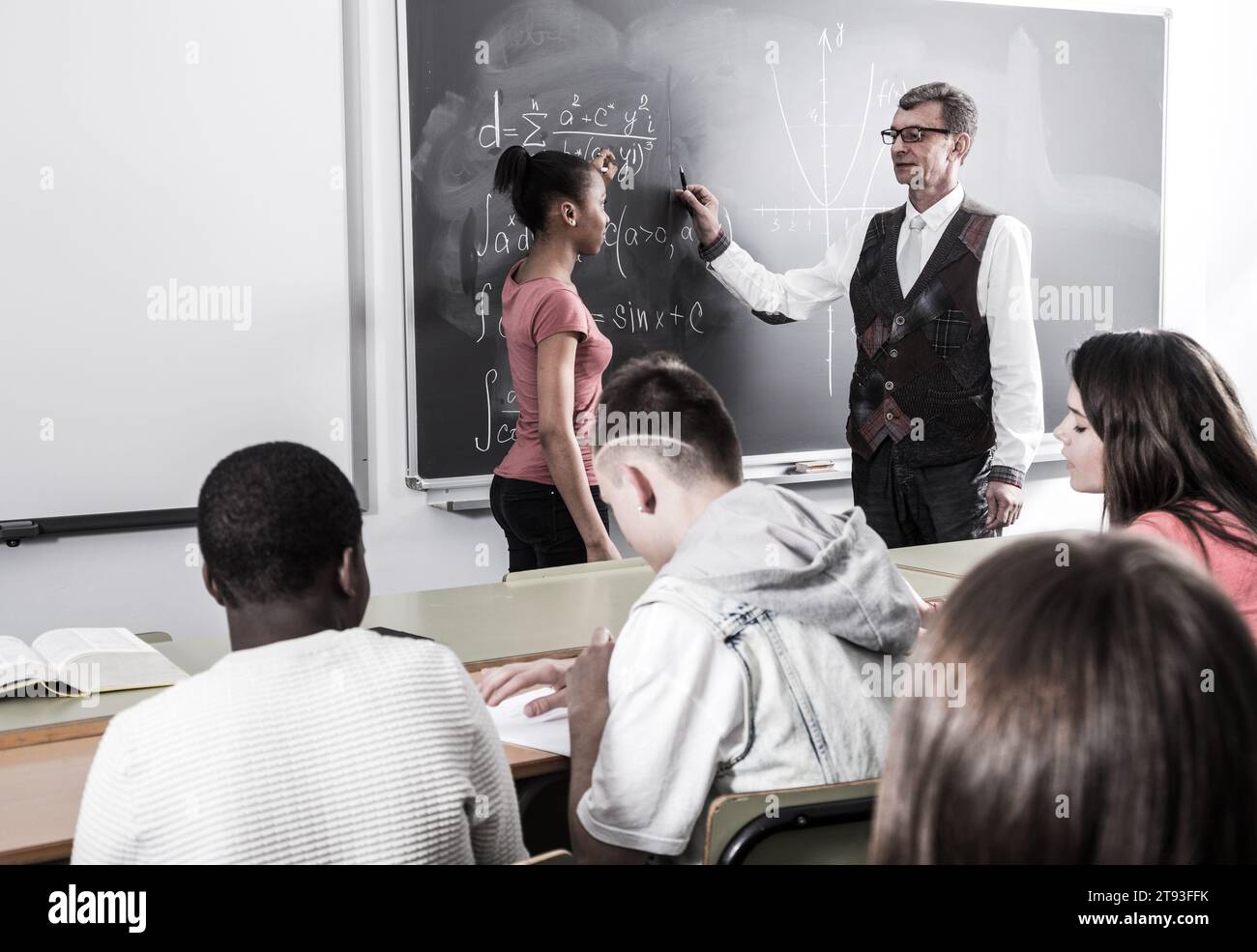 An African-American student answers at the blackboard in a math lesson ...