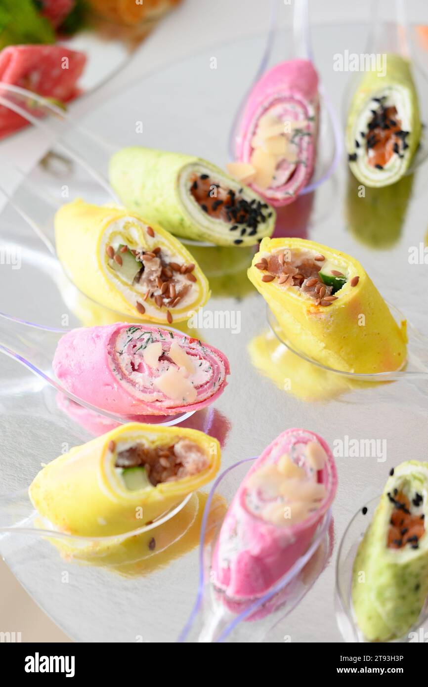 Cheese appetizer in rolls on small disposable spoons, roll in purple ...