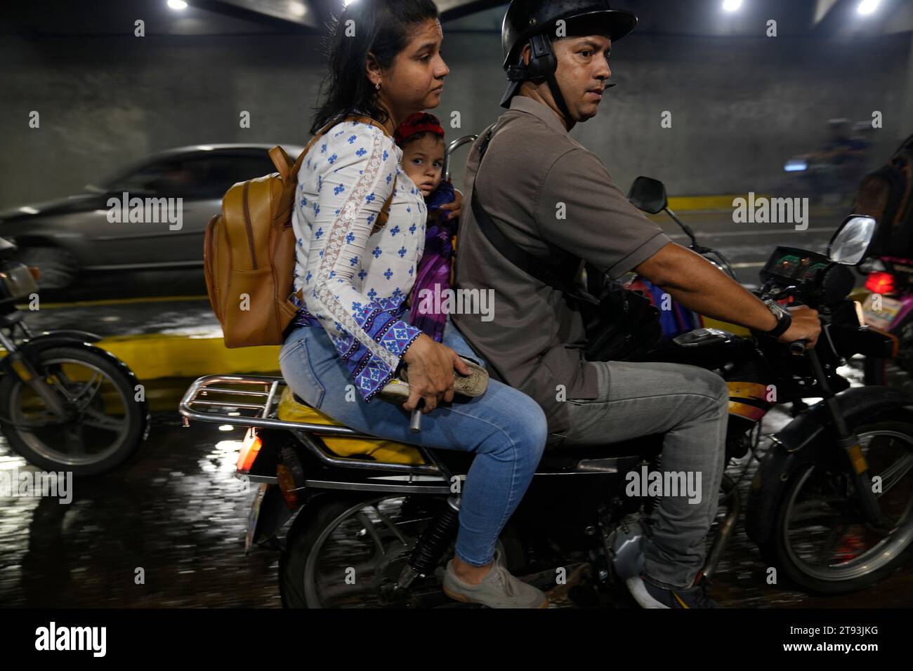 A woman and child ride on the back of a motorcycle in Caracas ...