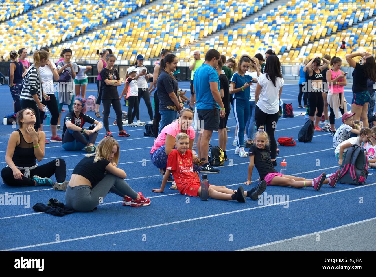 Kids and adult in tracksuits sitting on a track of a stadium before ...