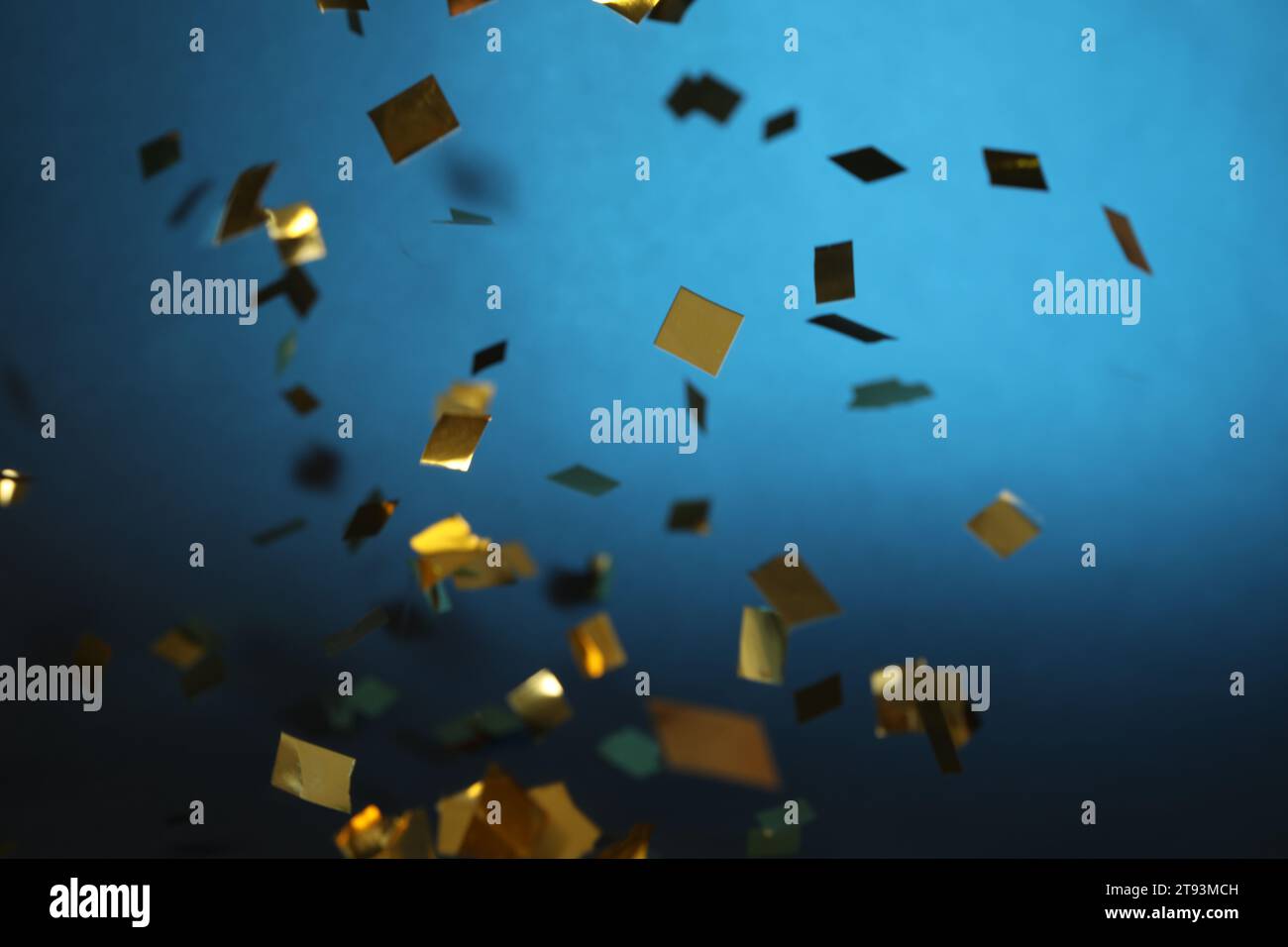 Shiny golden confetti falling down on blue background Stock Photo - Alamy