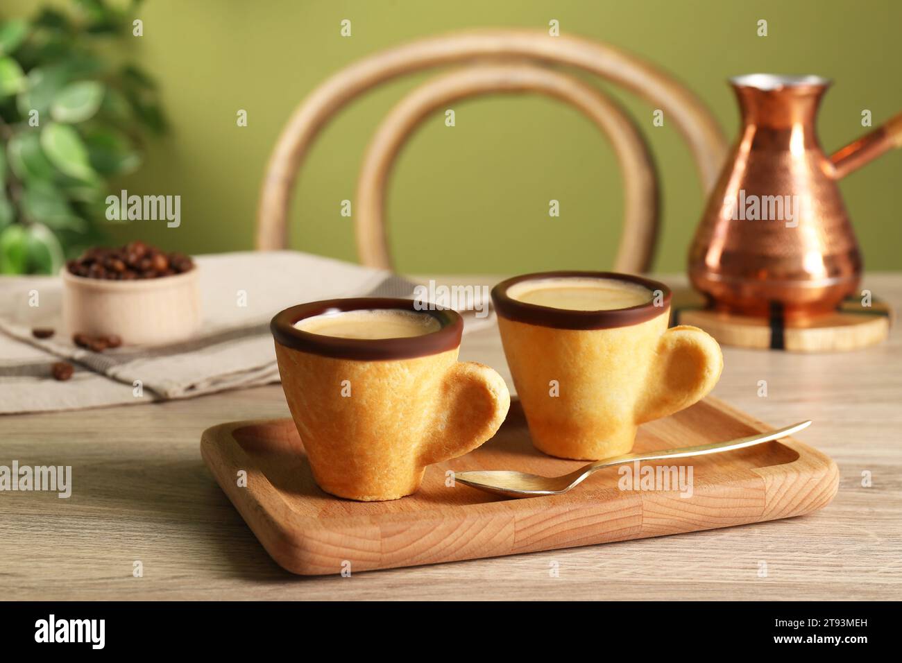 Delicious edible biscuit cups with coffee, spoon and board on wooden ...