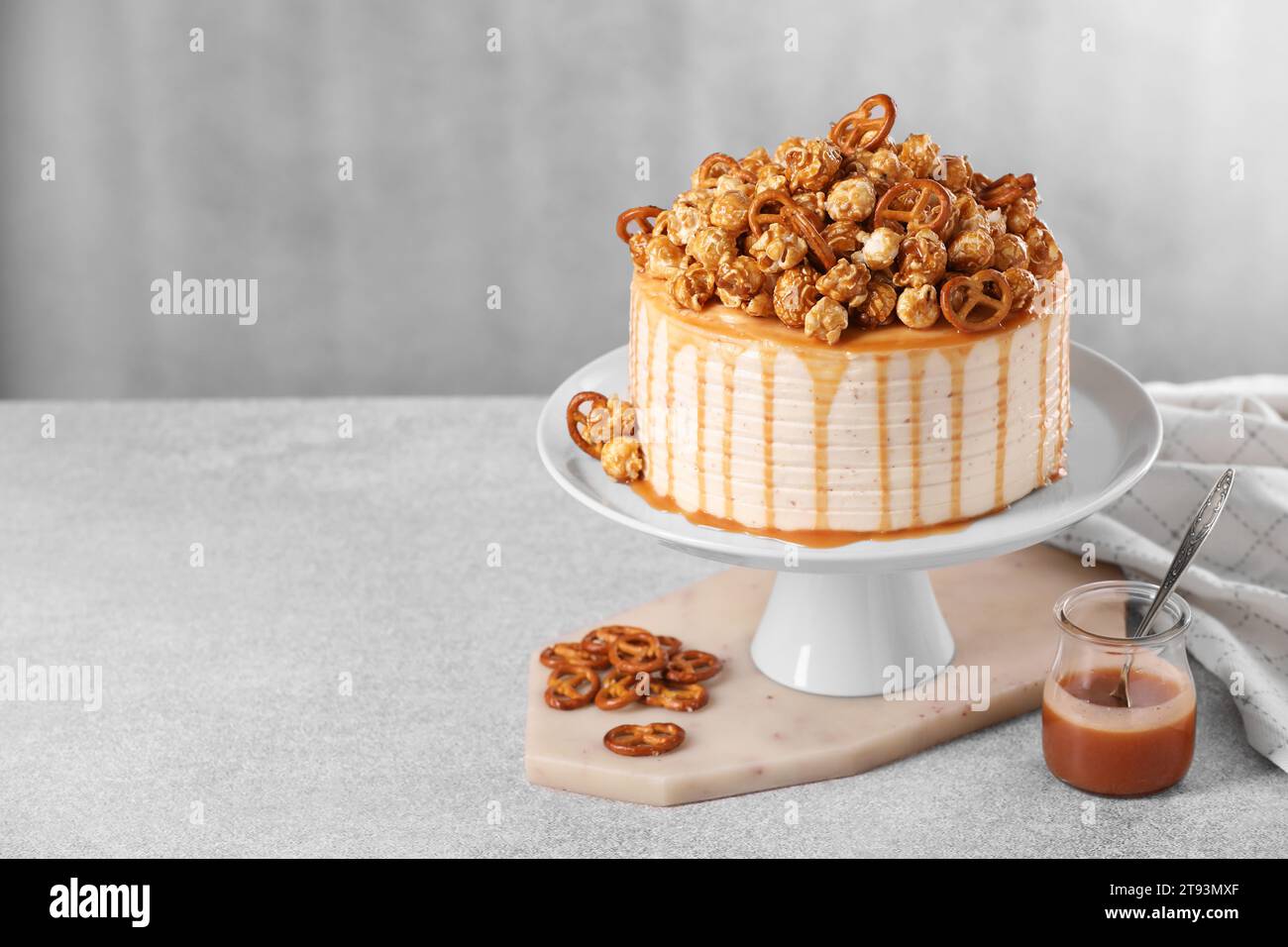 Caramel drip cake decorated with popcorn and pretzels on light table ...