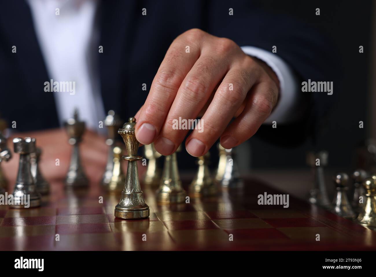 Man moving chess piece on checkerboard against dark background, closeup ...