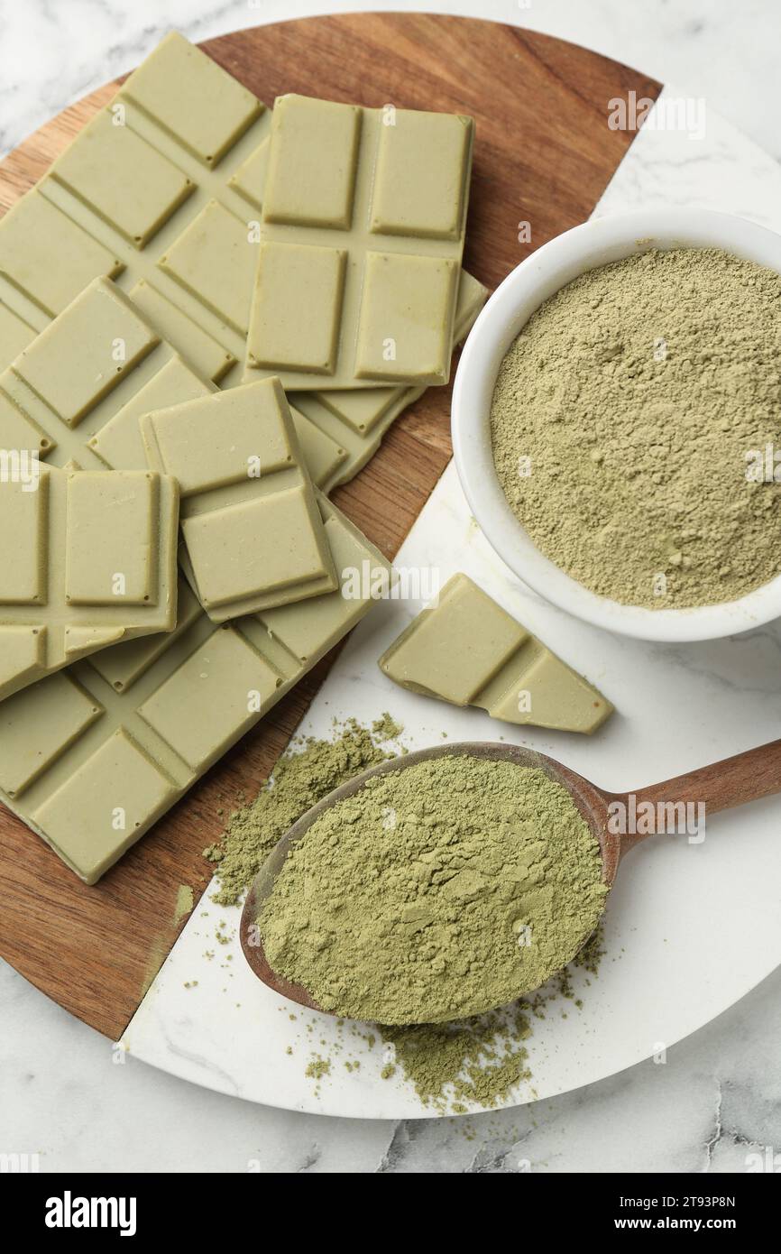 Pieces of tasty matcha chocolate bar and powder on white table, top ...