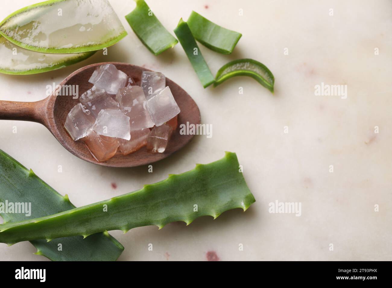 Aloe vera gel and slices of plant on light table, flat lay. Space for ...