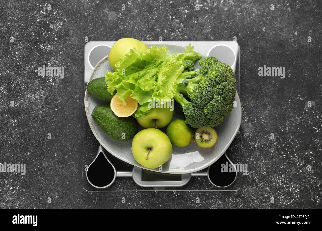 Healthy diet. Scale and fresh products on black textured table, top ...