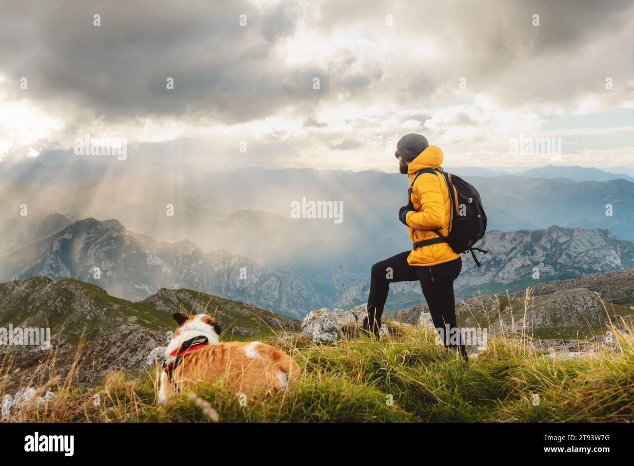 unrecognizable person with backpack, perched on a rock, contemplating ...