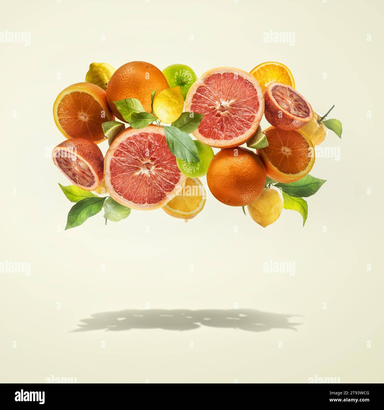 Group of flying various citrus fruits with green leaves at light yellow ...