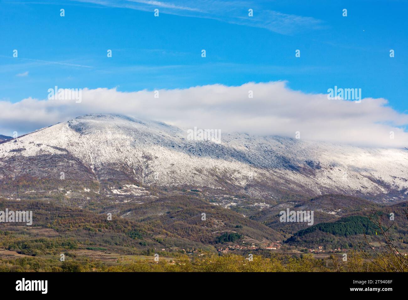 Snow draped summits of a dry mountain kissed by close passing white ...