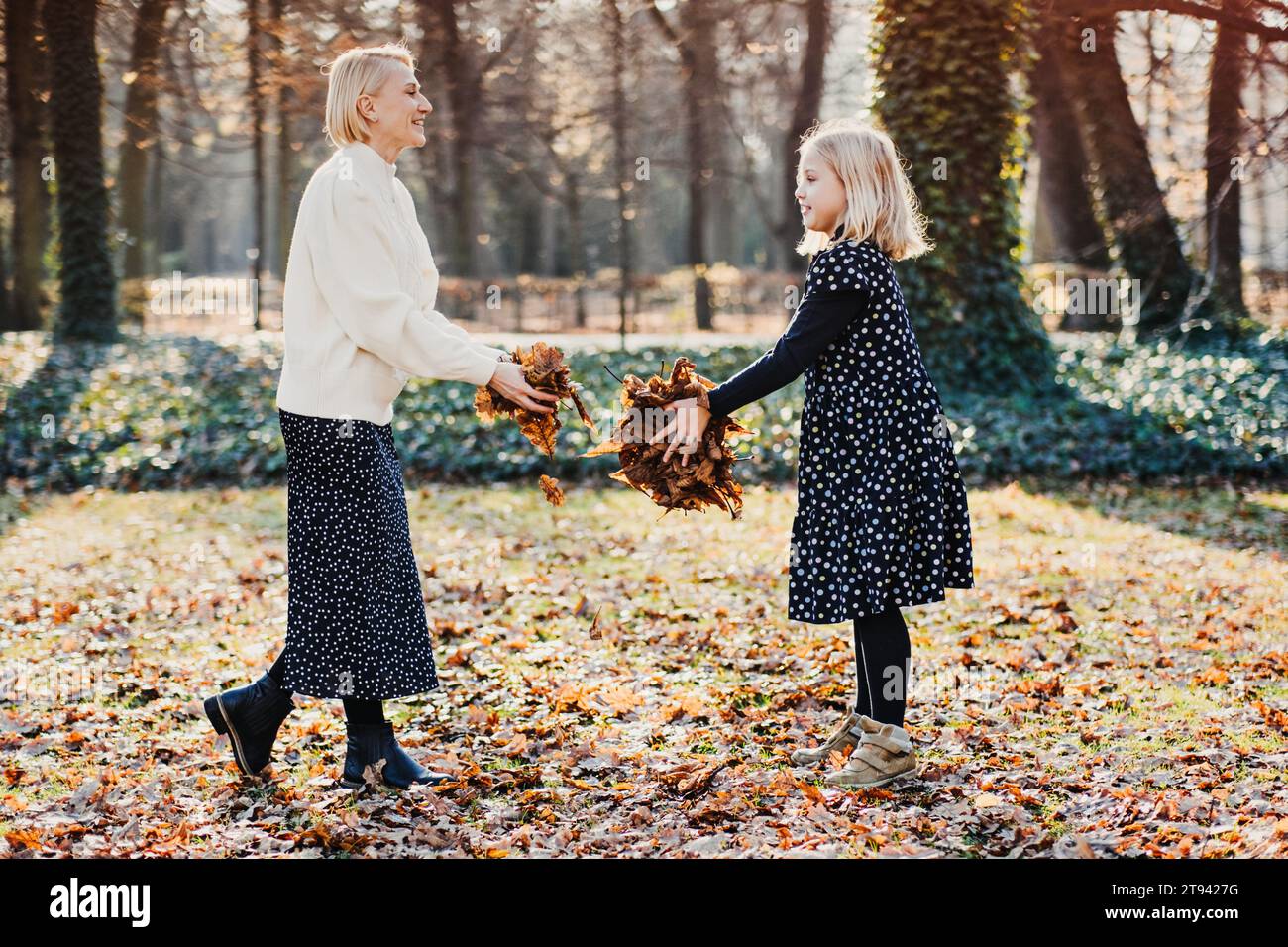 Autumn family walk. Heartwarming moment of smiling mother lovingly placing autumn leaf in ...
