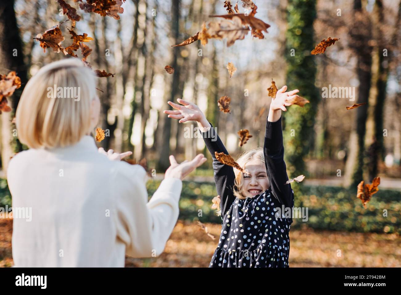 Autumn family walk. Heartwarming moment of smiling mother lovingly placing autumn leaf in ...