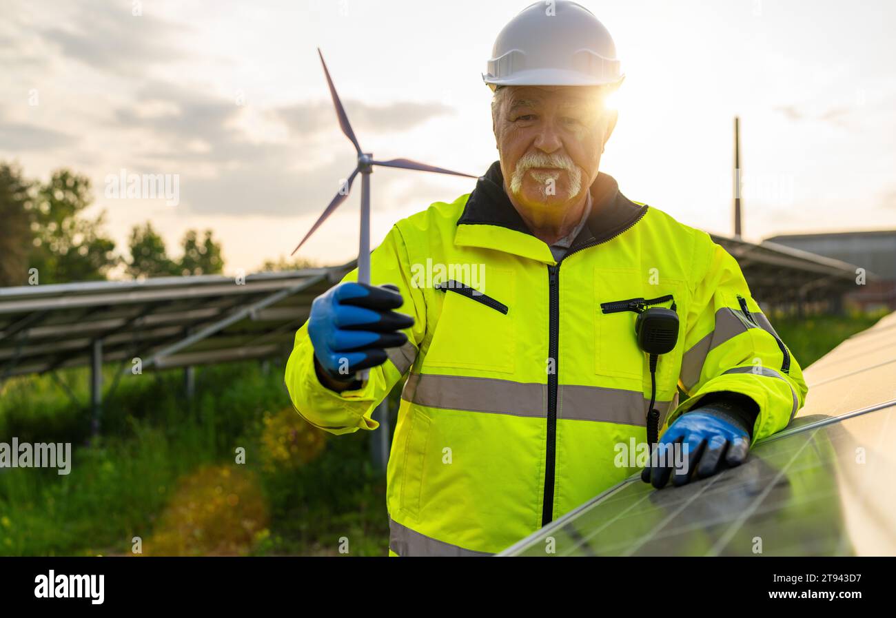 Senior engineer holding a wind turbine model at a solar photovoltaic ...