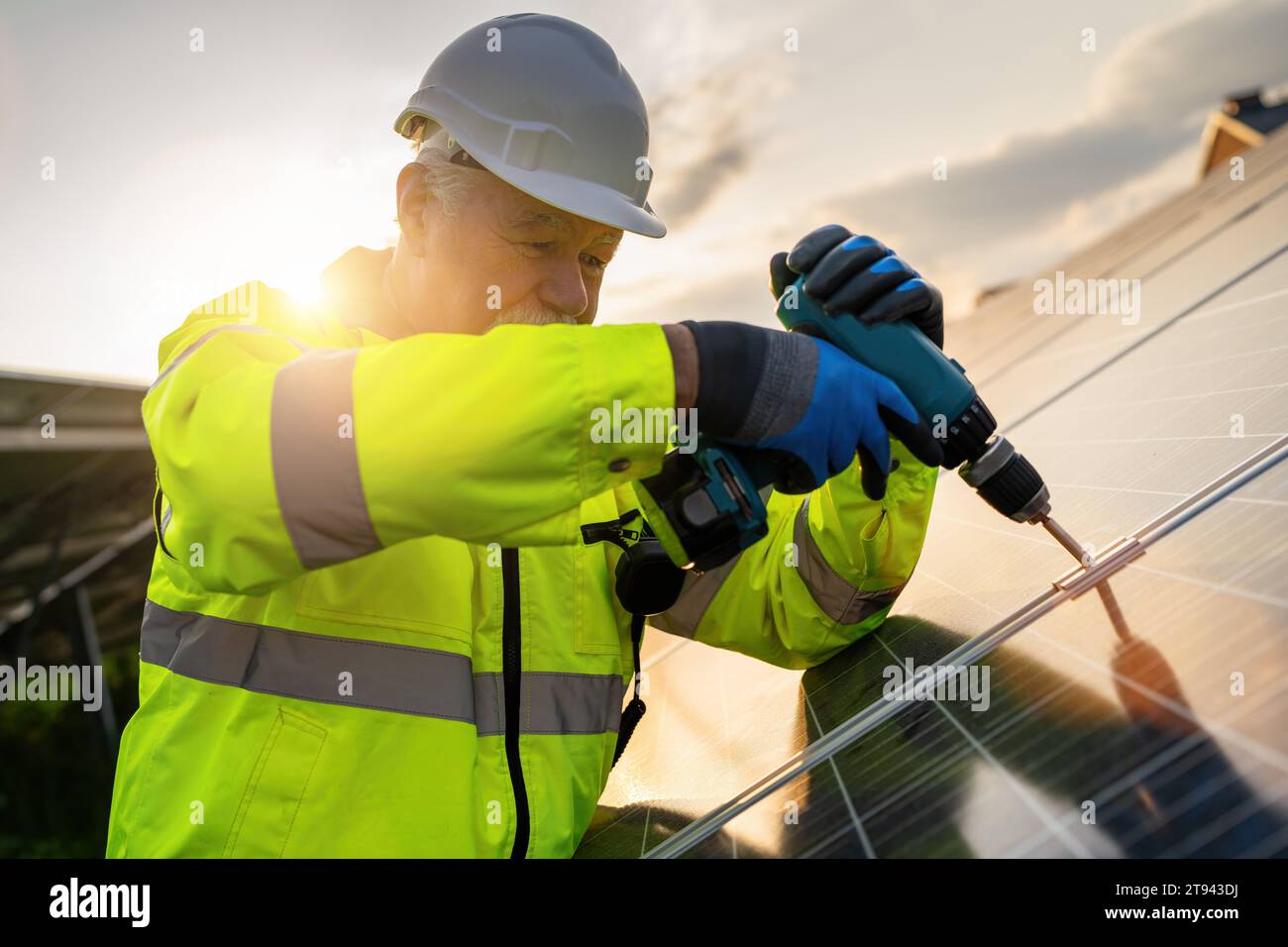 Engineer using a drill for solar panel installation at sunrise ...