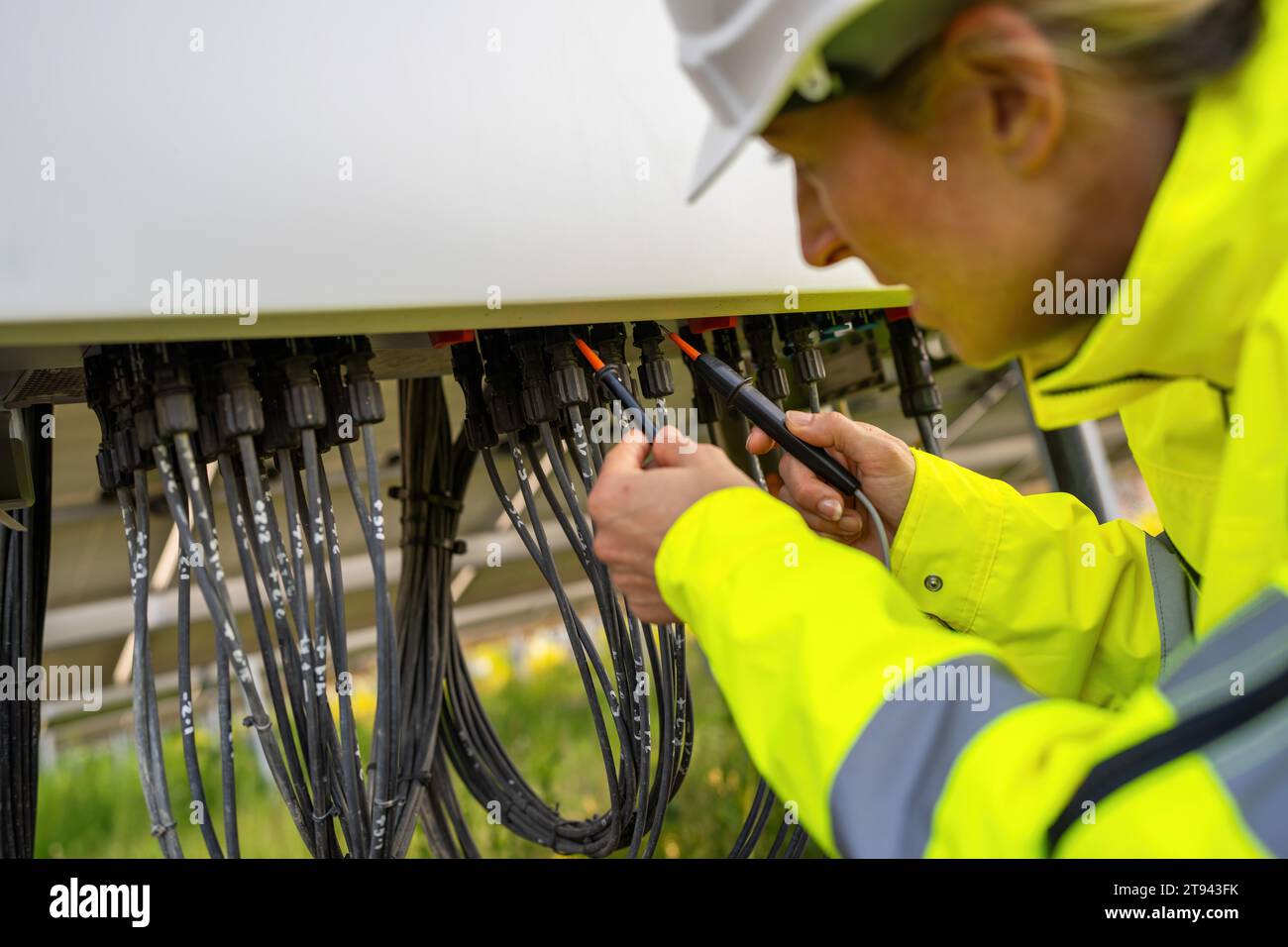 Technician using a voltage tester on a solar field's electrical ...