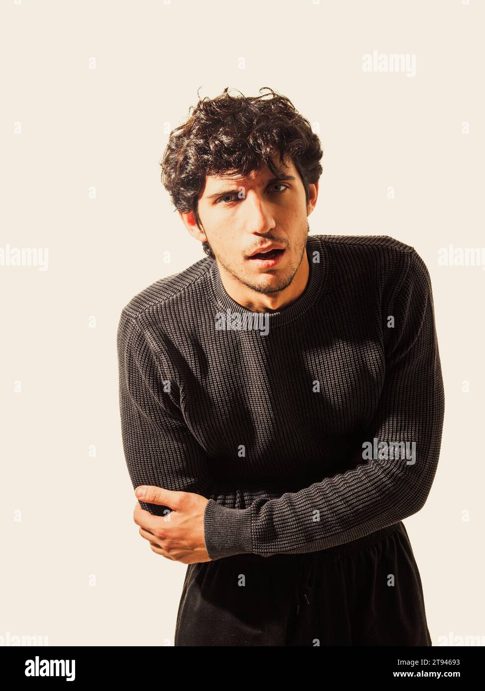 A young man is suffering from belly-ache, stomach ache, in a black ...