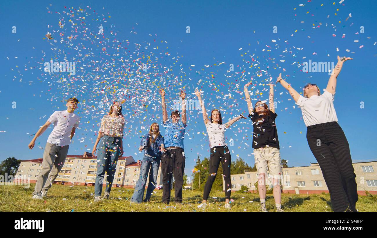 Friends toss colorful paper confetti from their hands Stock Photo - Alamy