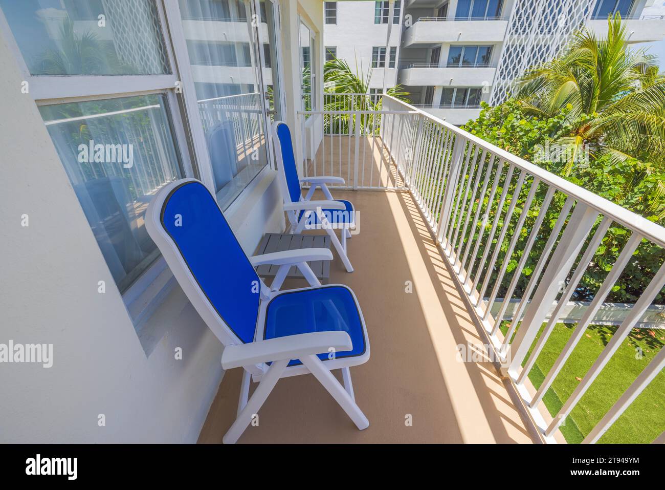 View of hotel balcony, furnished with blue chairs and table for ...