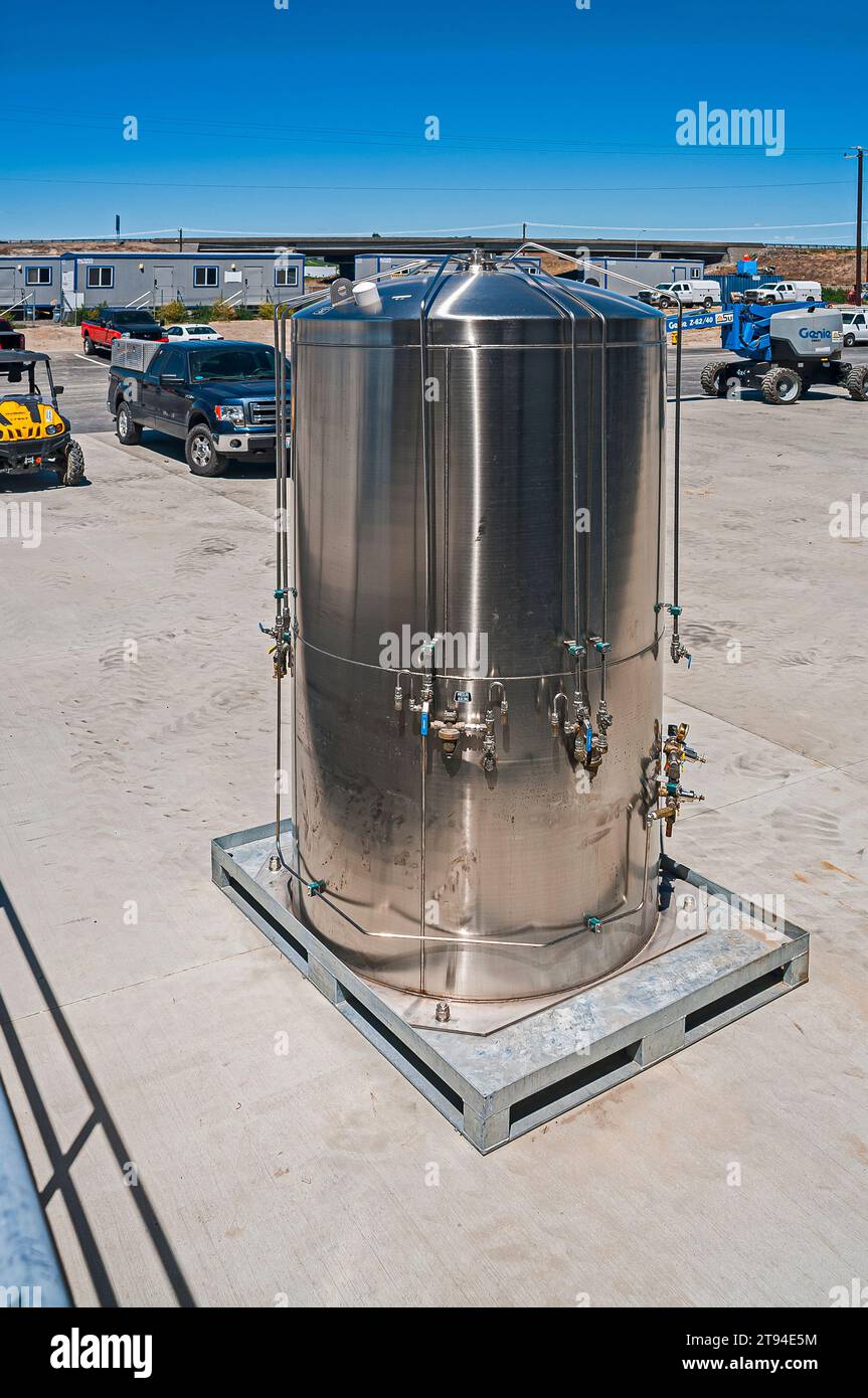 A stainless-steel tank, outdoors on a metal pallet at an CO2 industrial ...