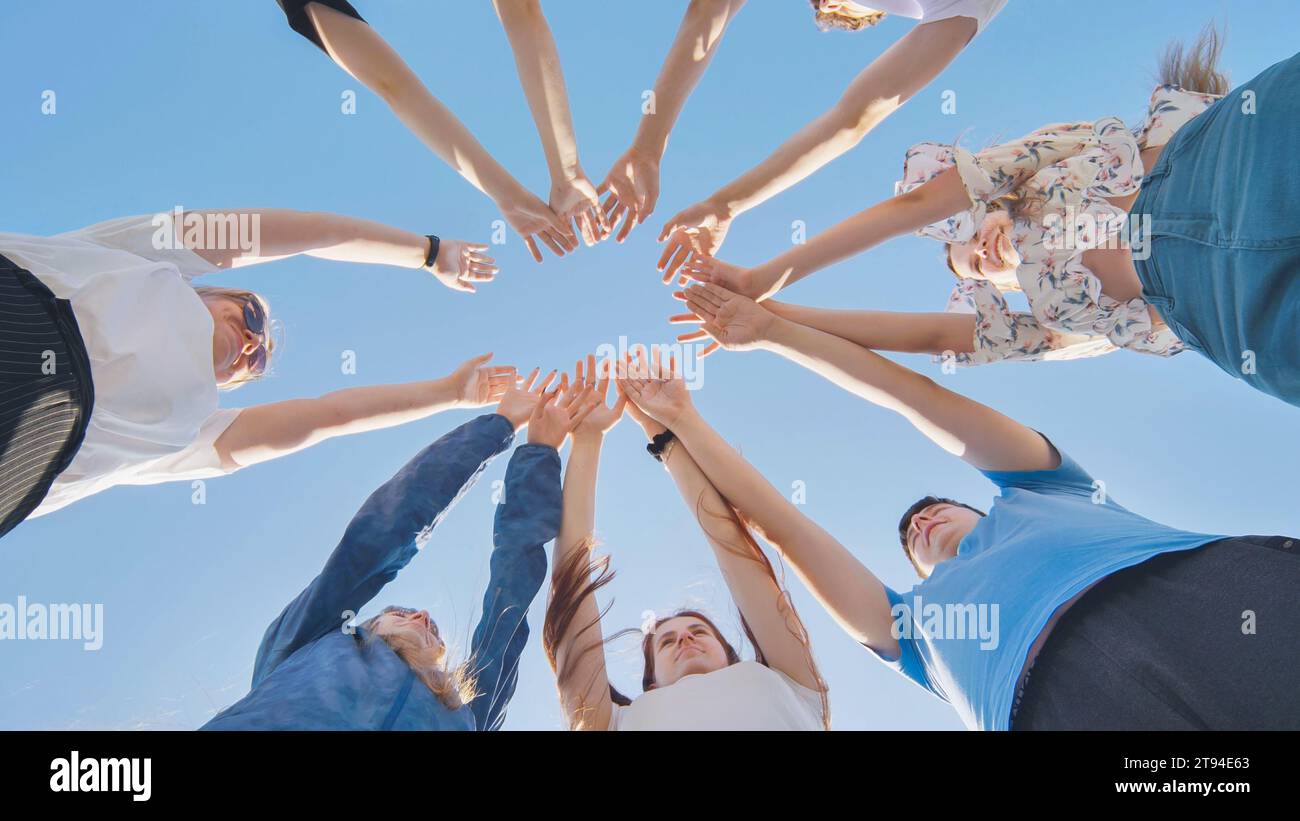 Friends putting their hands together in a sign of unity and teamwork ...