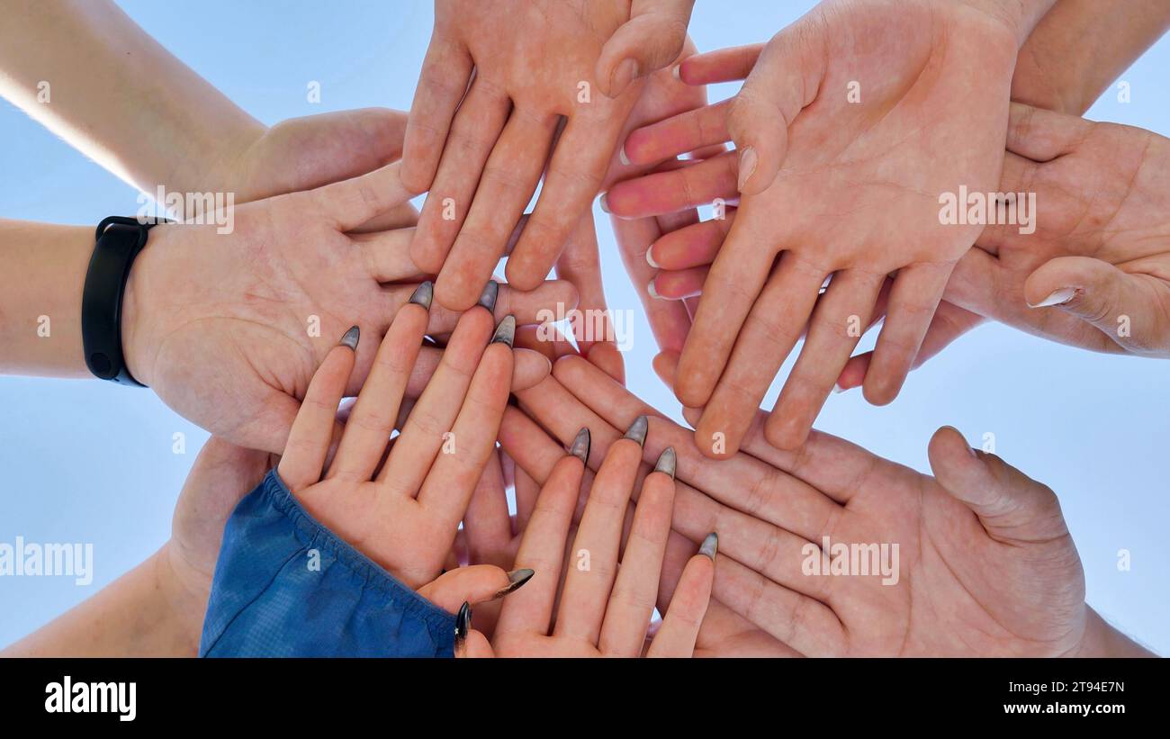 Friends putting their hands together in a sign of unity and teamwork ...