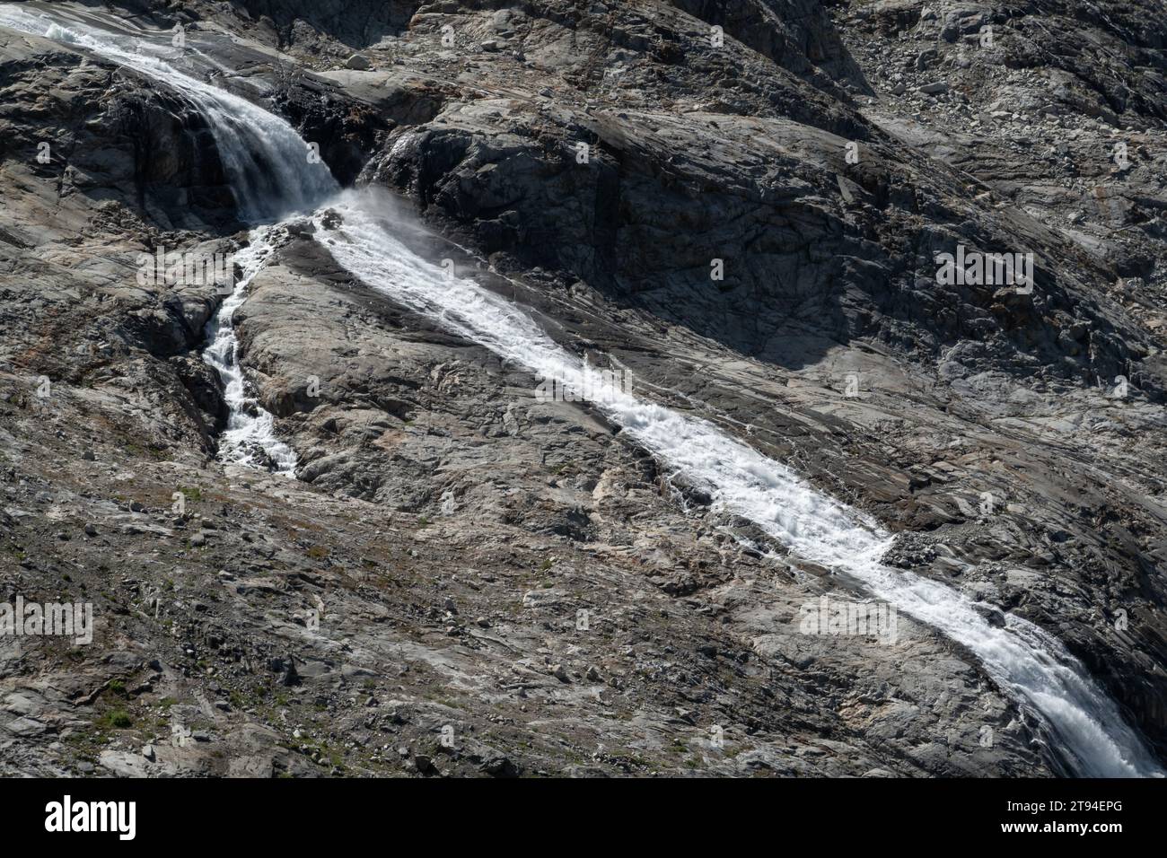 Glacial melt water streaming over eroded granite rock face in a ...