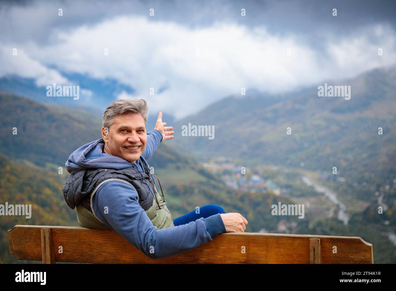 A male traveler sits on an observation deck bench, gazing at the ...