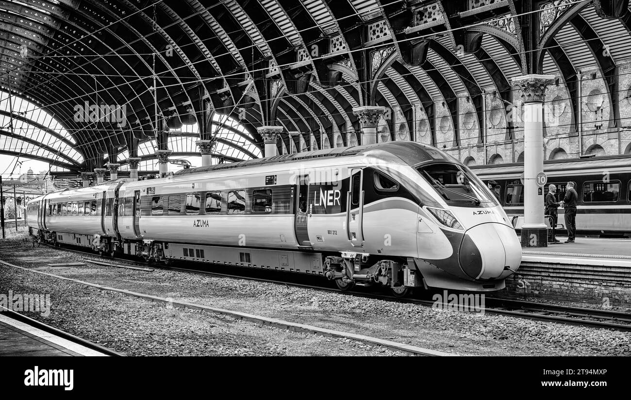 A modern train stands at a historic railway station platform under a ...