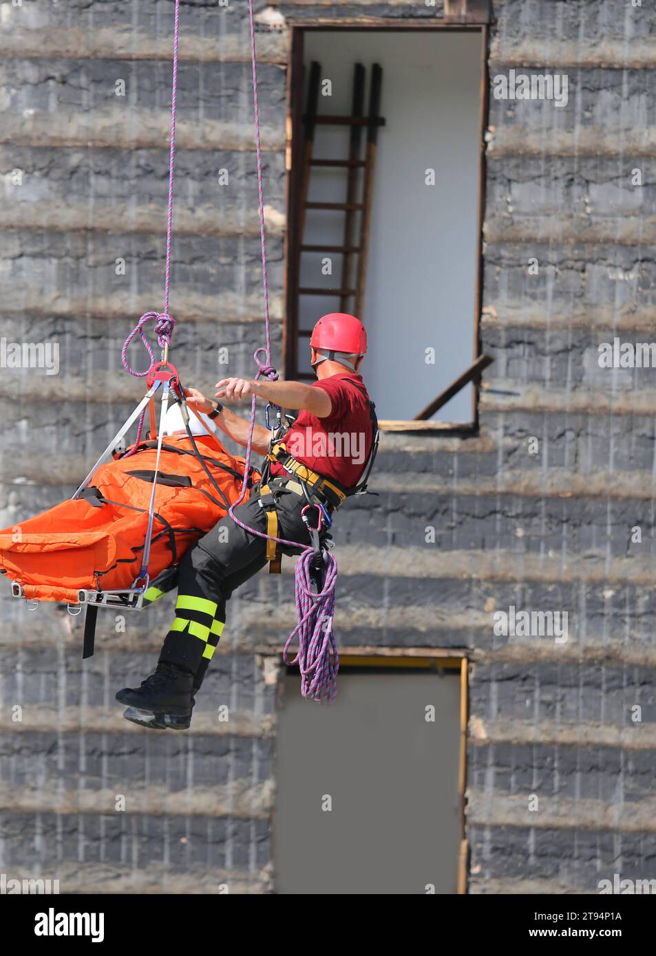 Brave harnessed firefighter lowers down with ropes during the transport ...