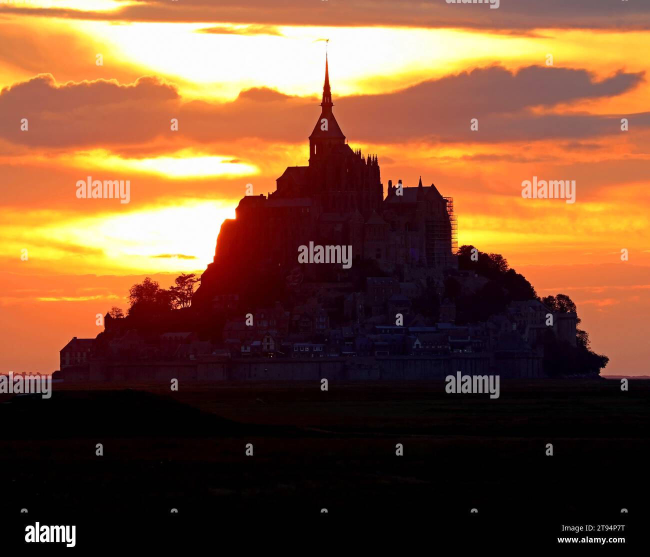 Sun sets behind the black silhouette of the ancient Abbey of Mont Saint ...